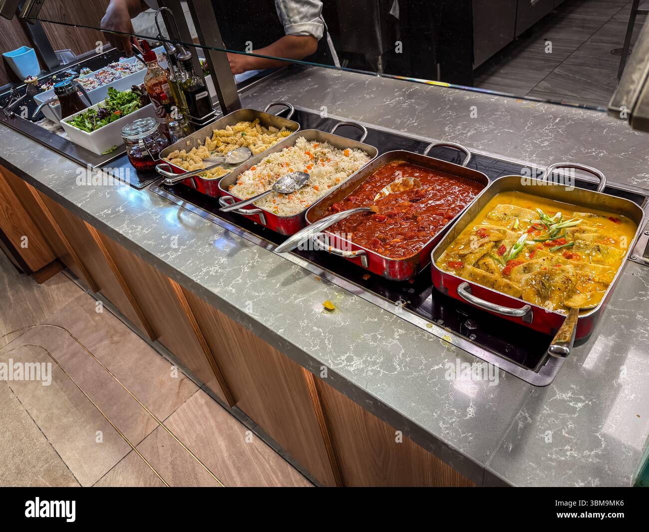 Self-serve buffet counter featuring various hot food trays, a salad bar ...