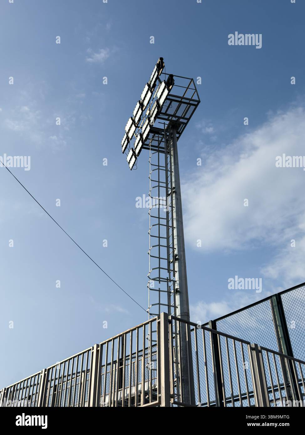 Metal floodlight tower with LED panels against blue sky, photographed ...
