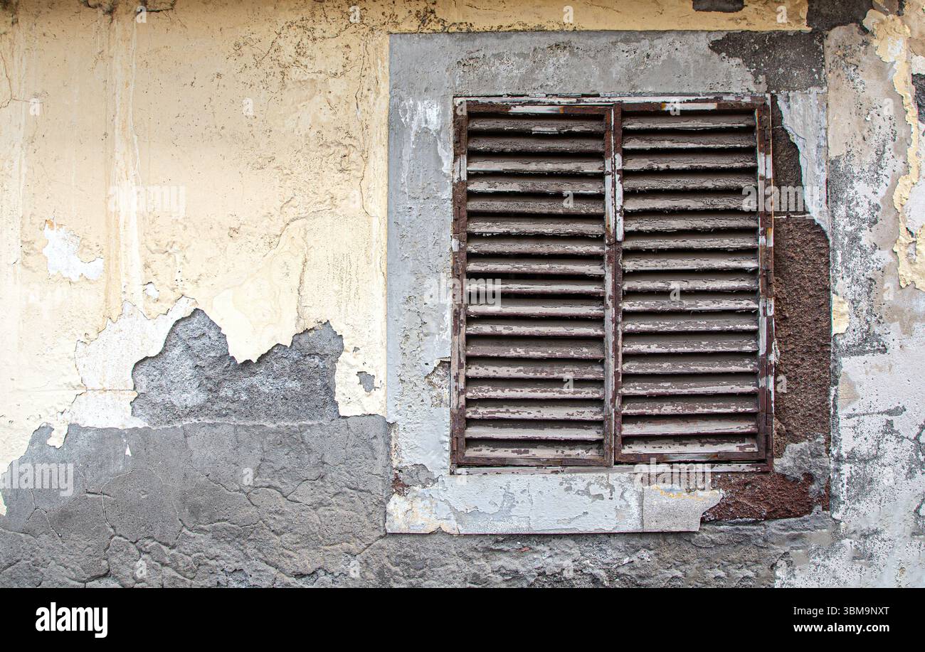 Rusty metal ventilation window on a decaying exterior wall with damaged ...