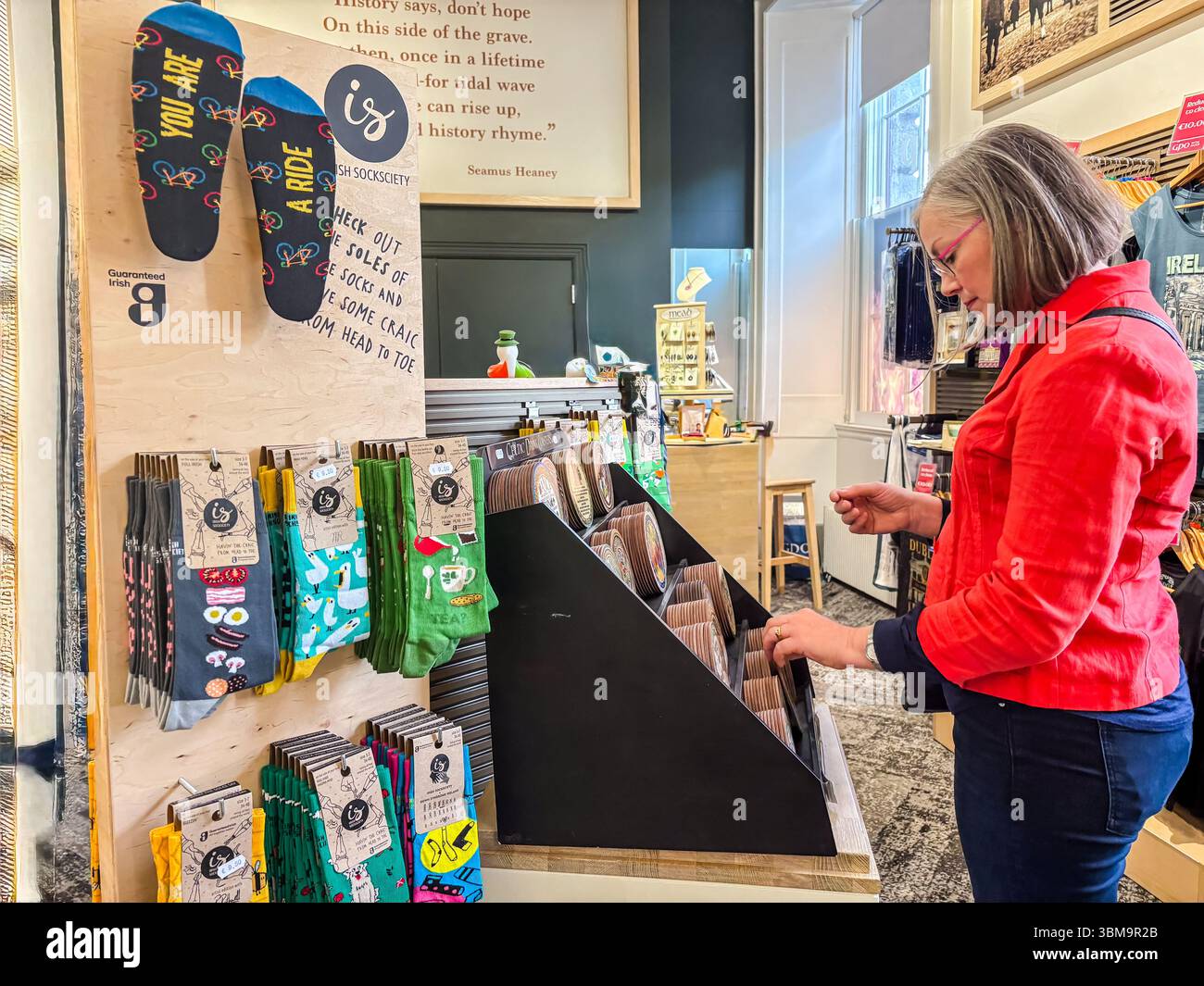 Mature woman browsing gift shop display with socks and souvenirs inside ...