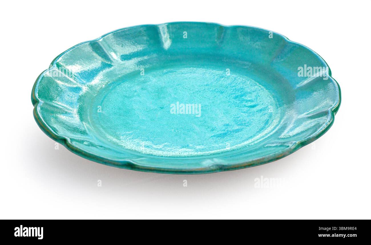 Studio shot featuring an empty, teal ceramic plate with a scalloped edge, set against a clean ...