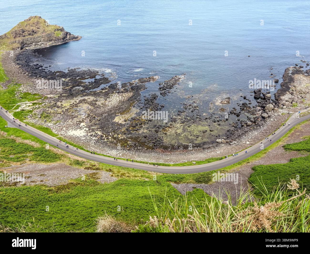 Giant's Causeway coastal road with tourists walking along the dramatic ...