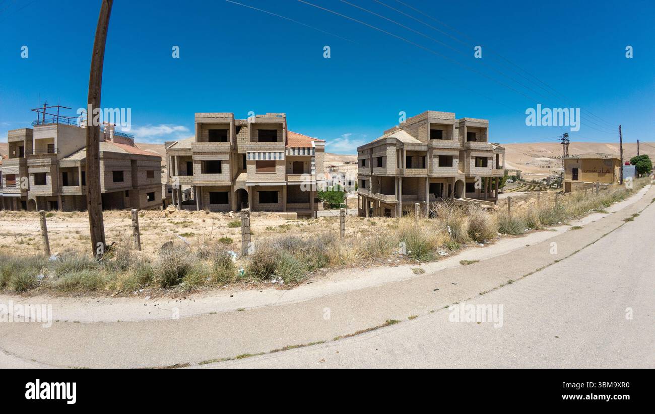 A panoramic view of unfinished concrete buildings in a rural area, with ...