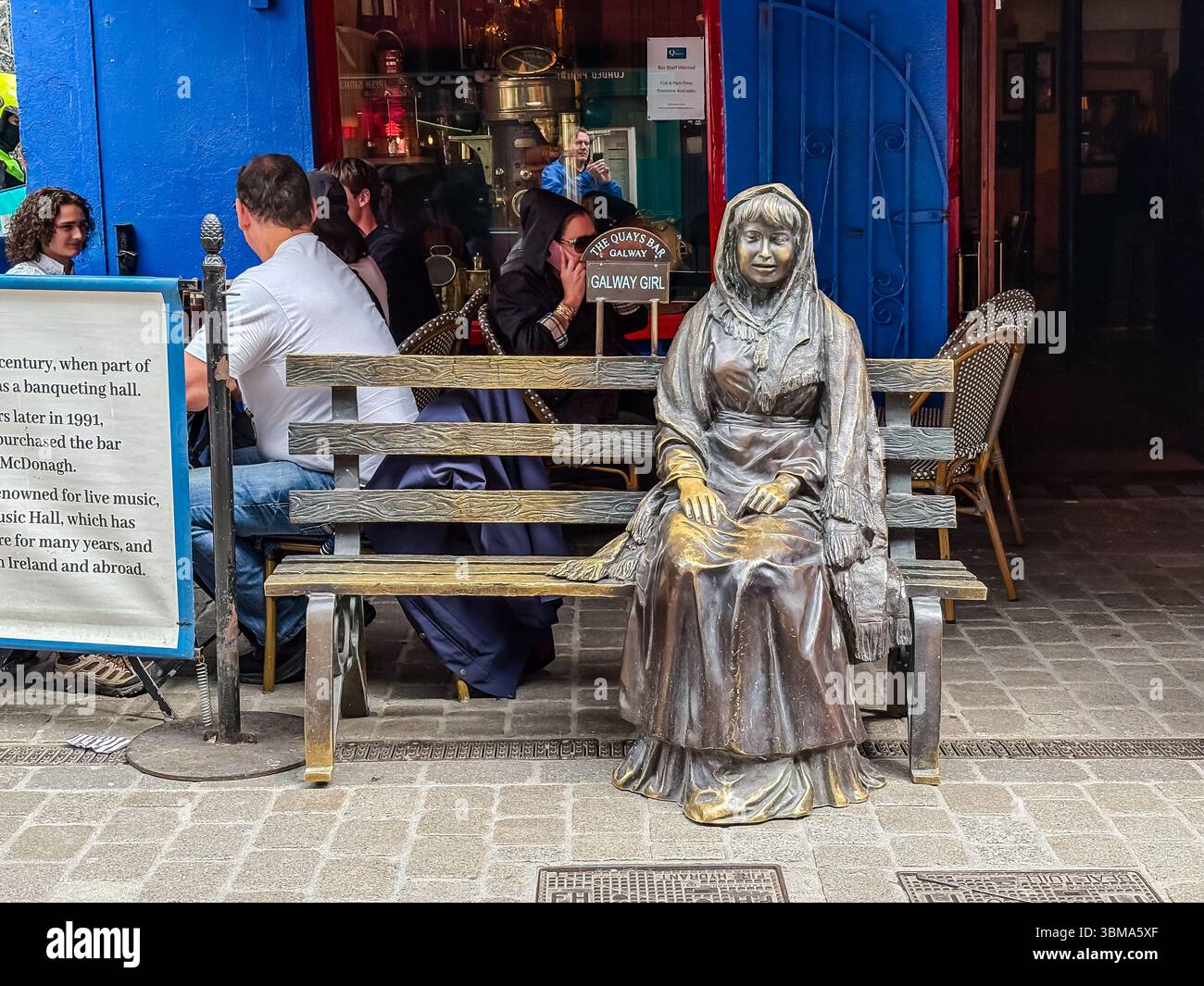 Bronze statue of a seated woman on a bench in the street in Galway ...