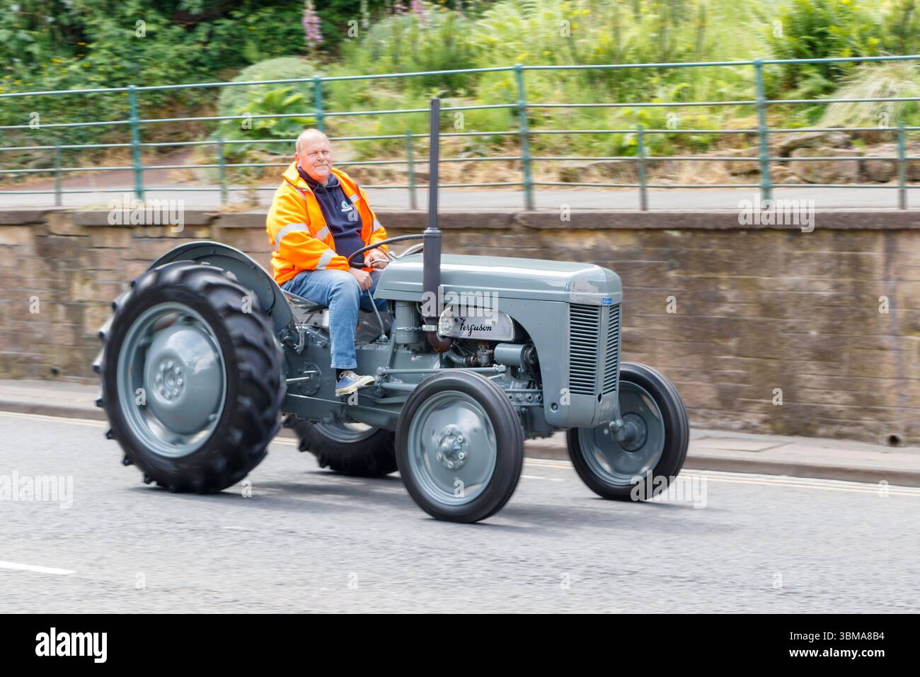 Man wearing an orange jacket driving a vintage grey Ferguson FE-20 ...