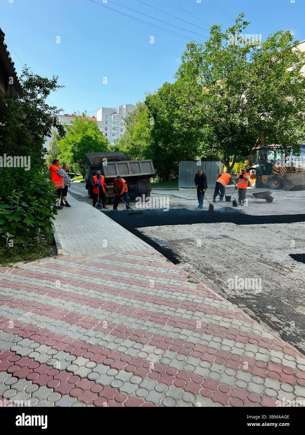 Kyiv, Ukraine - June 24, 2025: Construction workers laying asphalt on a ...