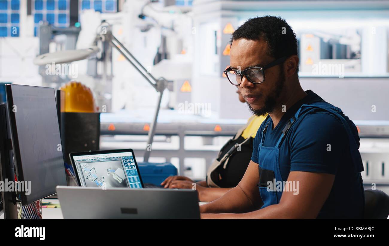 Black Engineer Inputs Solar System Parameters At Industrial Workstation