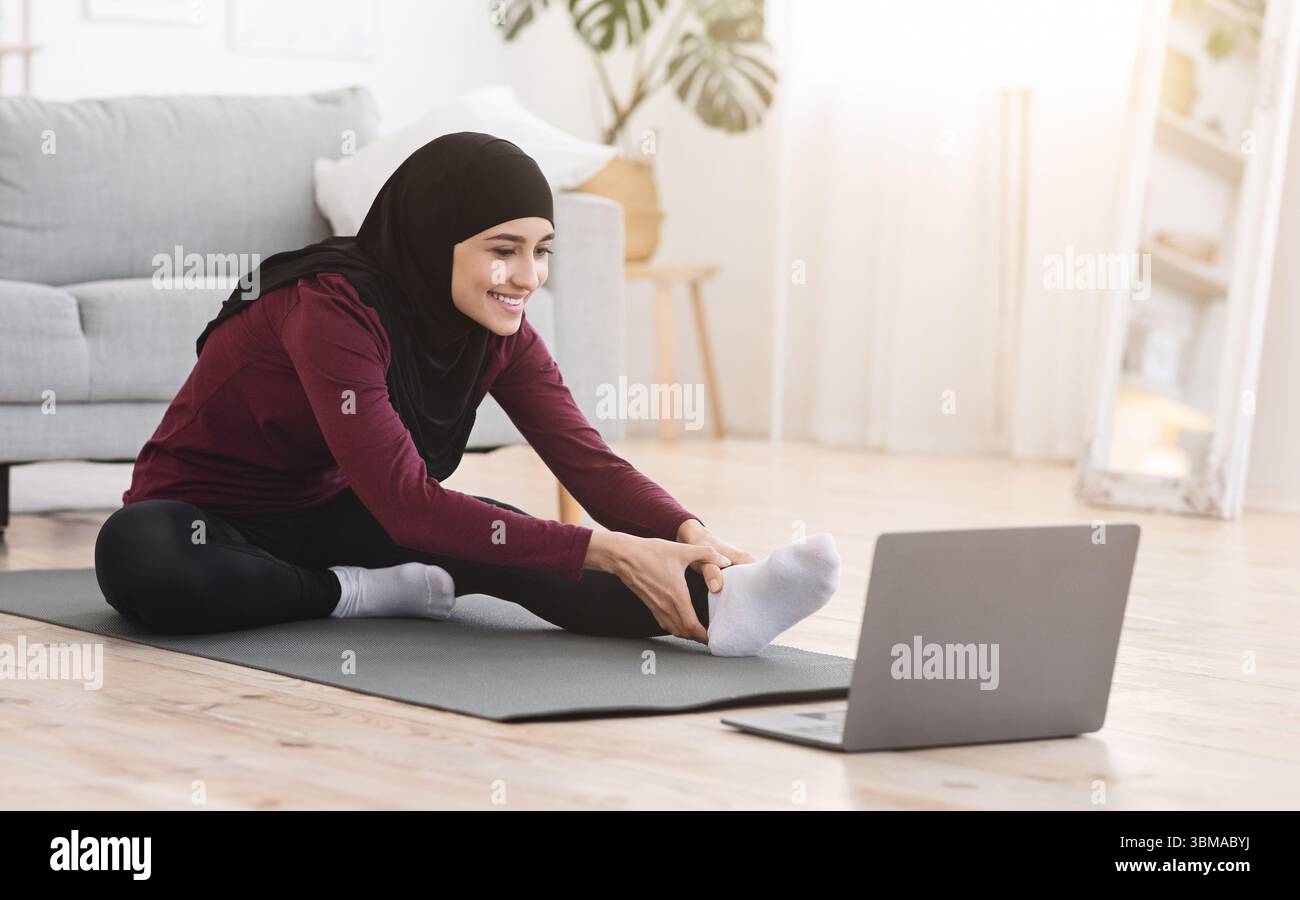 Home Pilates. Sporty arabic woman stretching leg muscles in front of ...
