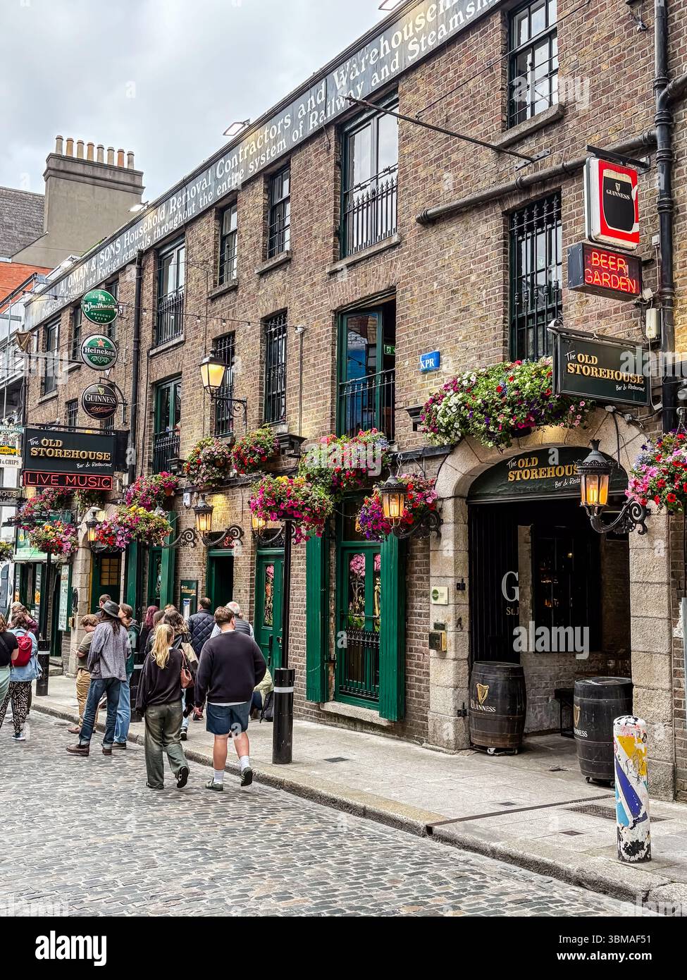 The Old Storehouse pub, a brick building with green shutters and flower ...