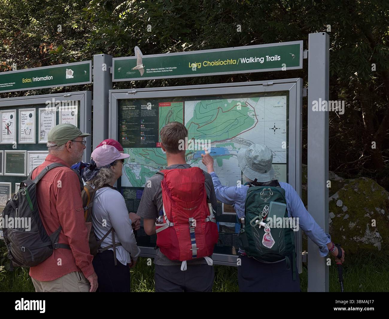 Hikers and tourists study a walking trails map board in Wicklow ...
