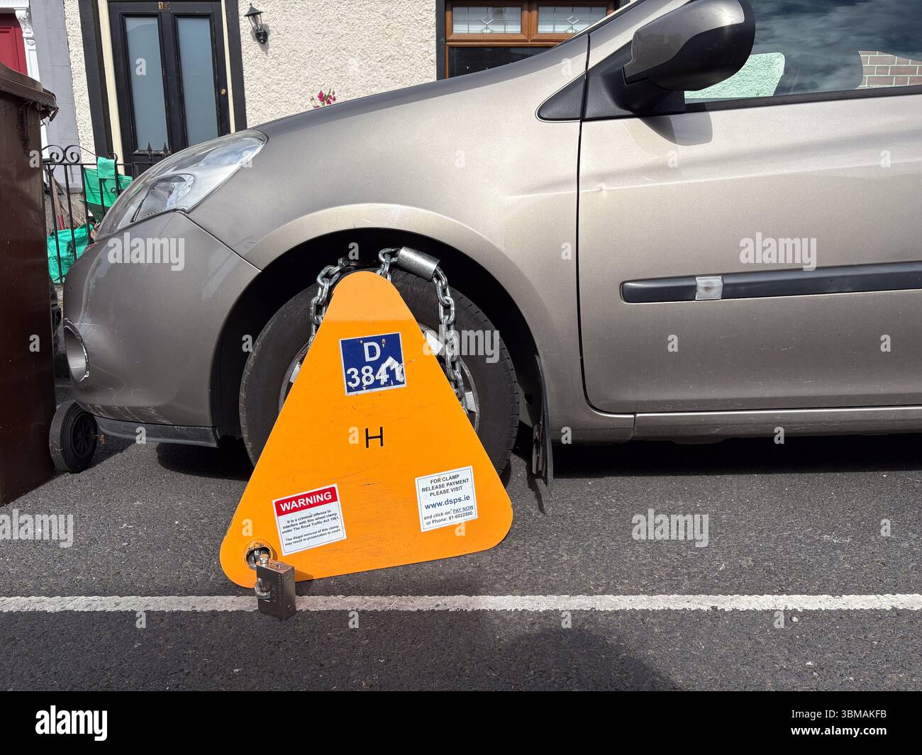 Car wheel clamped in Dublin. Shows a car wheel locked by an orange ...
