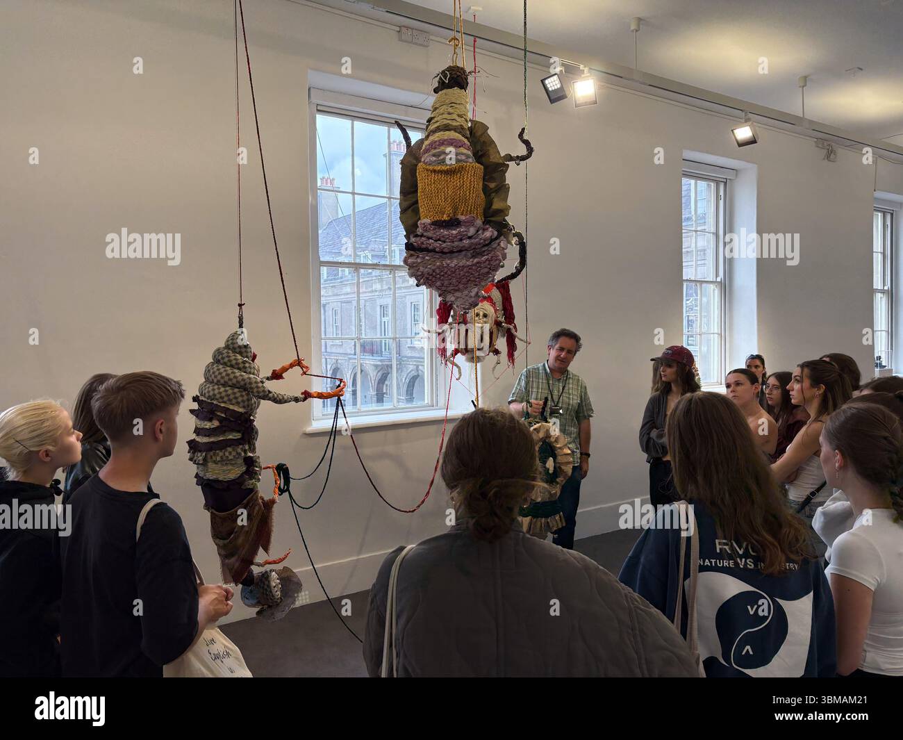 Group of students and teacher view modern art installations inside a ...