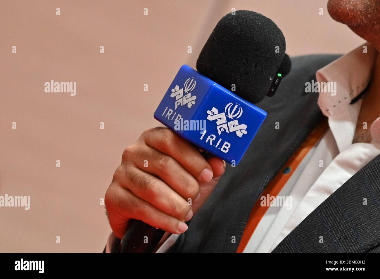26 June 2025, China, Qingdao: A man holds the microphone of the Iranian ...