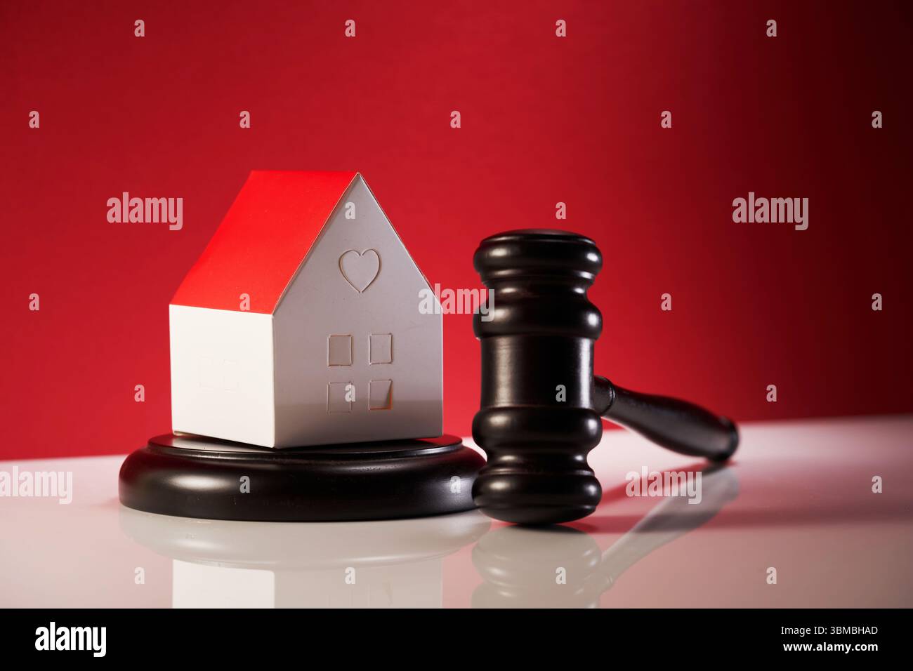 judge's gavel and small model house on mallet against red background ...