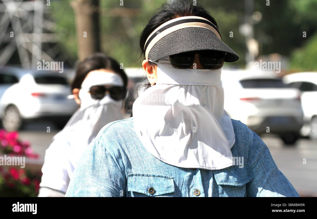 People wearing sun protective clothing on a street in Shenyang City ...