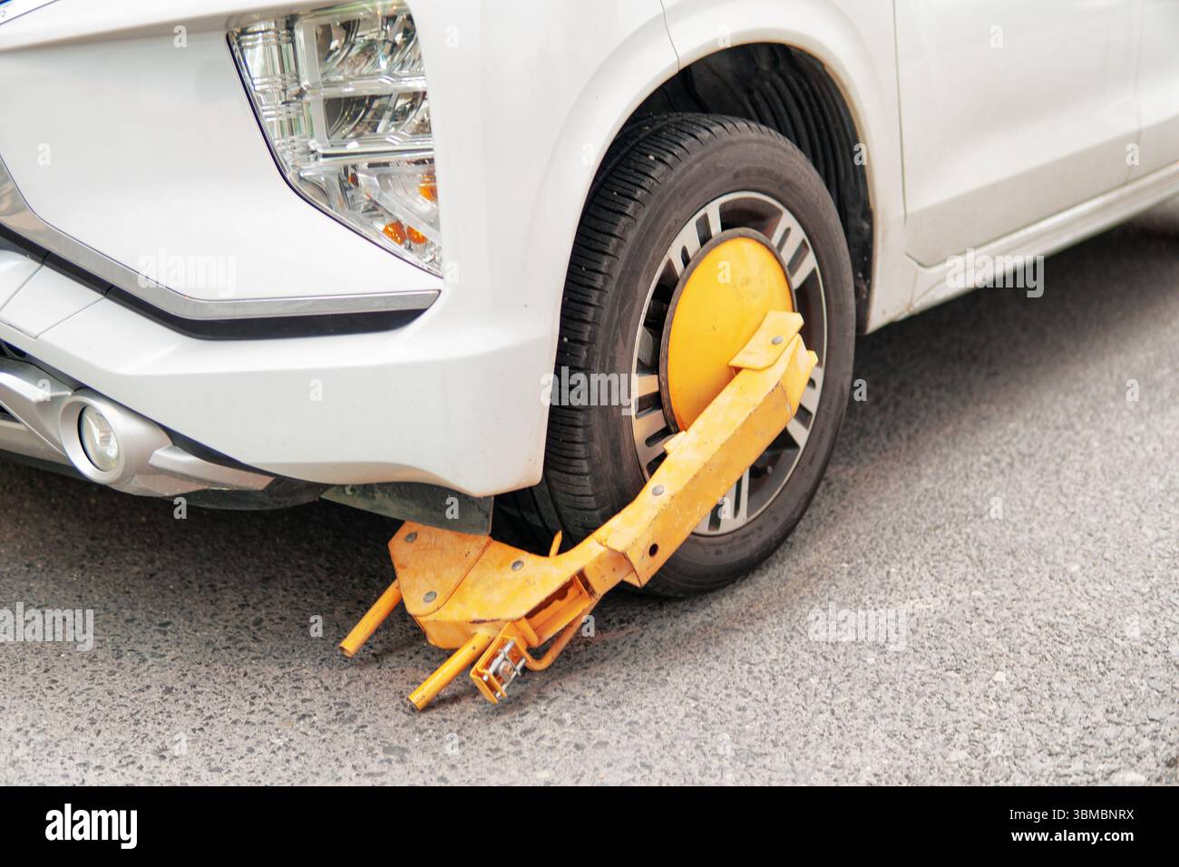 Yellow wheel clamp on an illegally parked car Stock Photo - Alamy