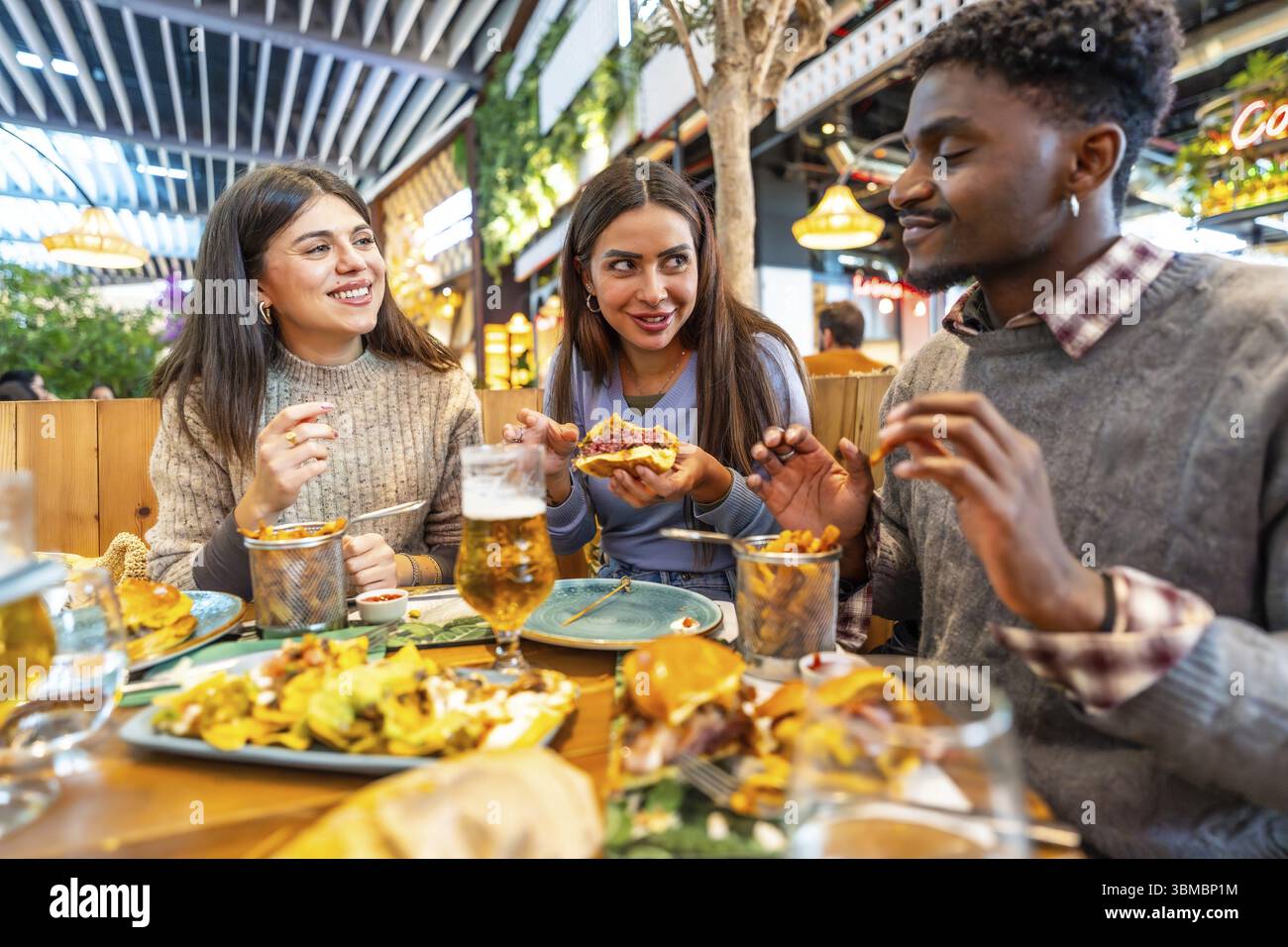 Group of happy multiethnic friends enjoying a meal together, eating ...