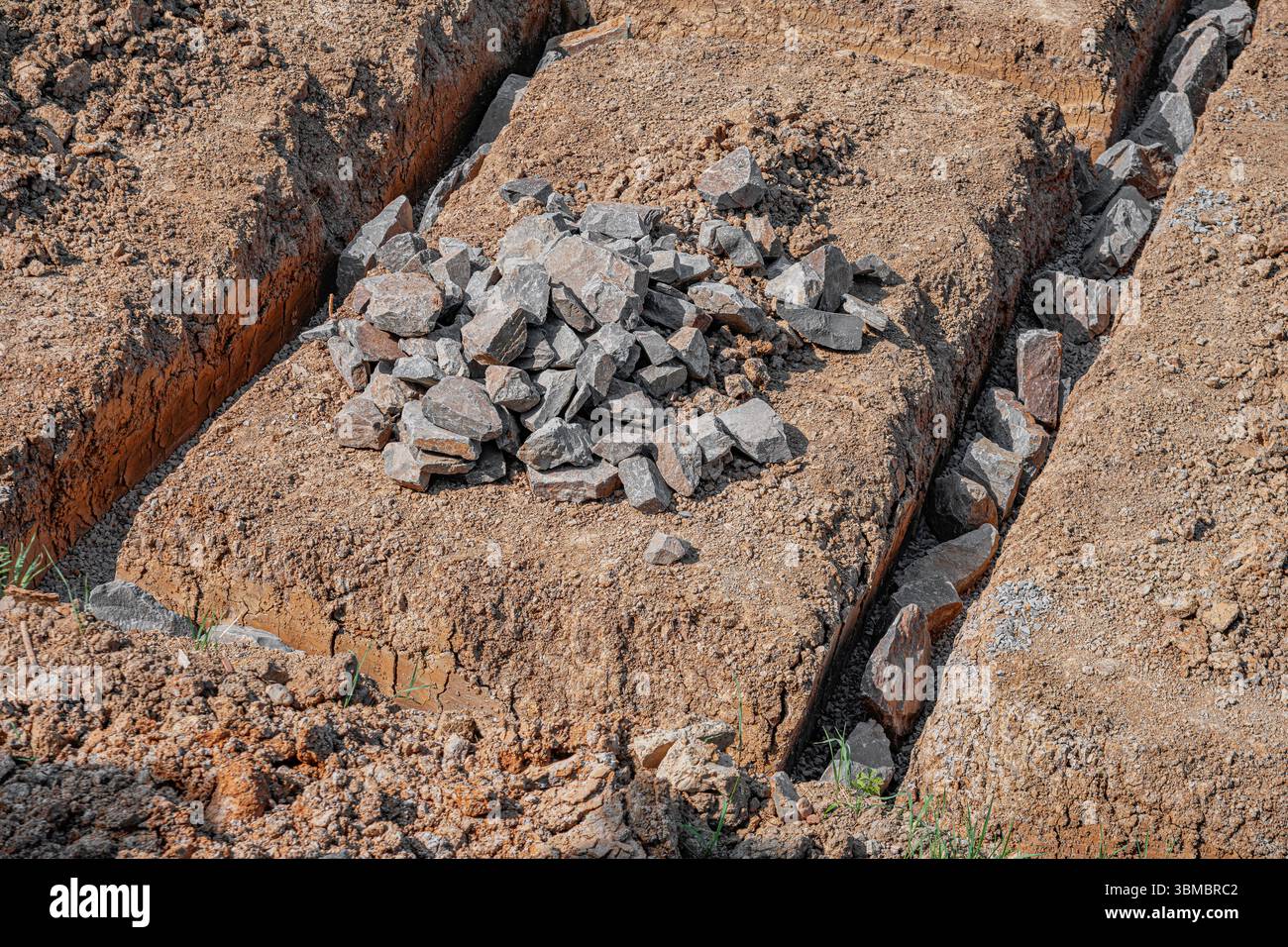 An outdoor construction site shows freshly dug trenches filled with ...