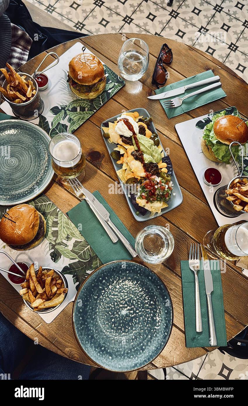 Top view of a wooden restaurant table with nachos, burgers, french ...