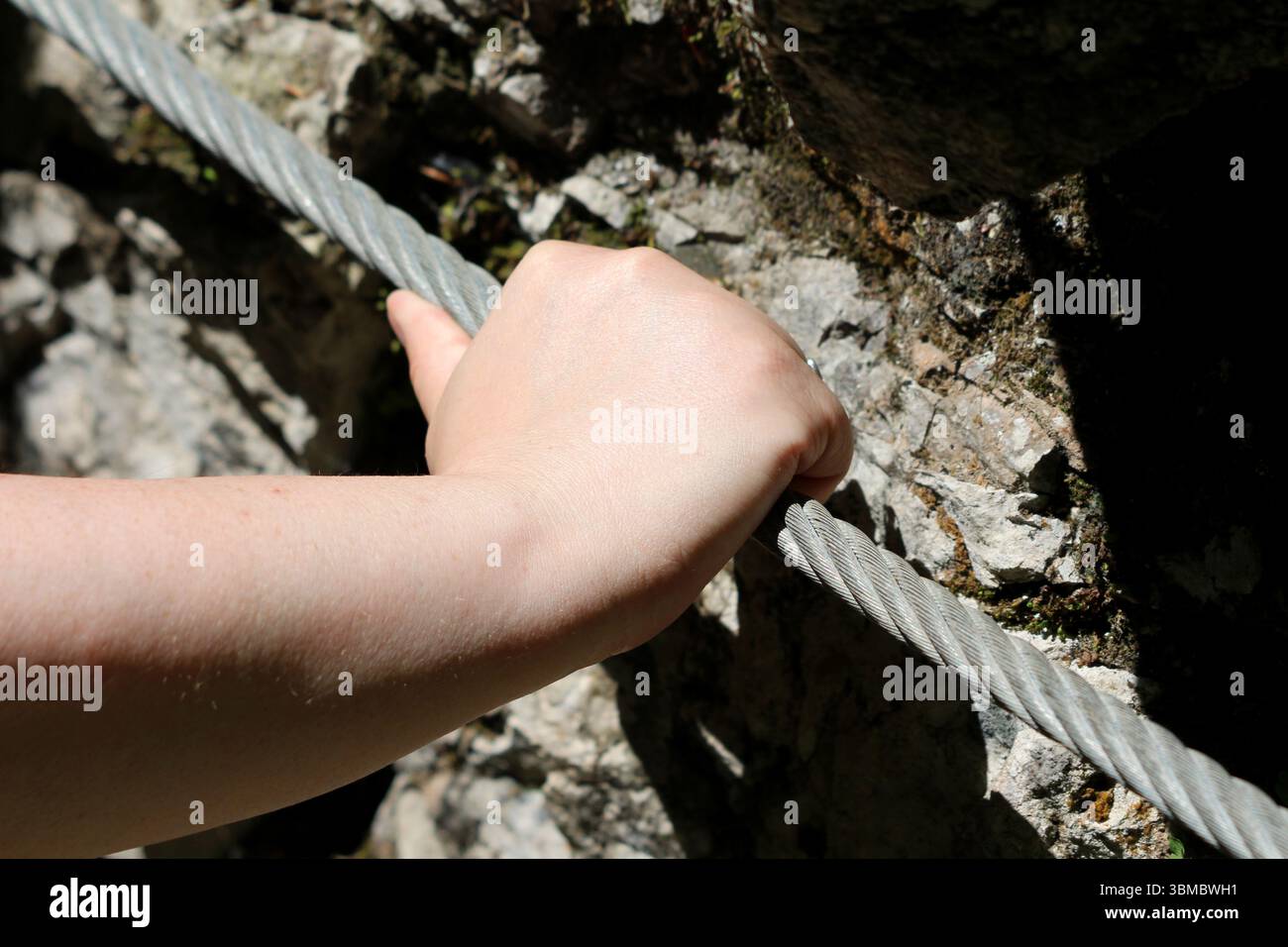 Close-up of a hand firmly holding a thick steel cable attached to a ...