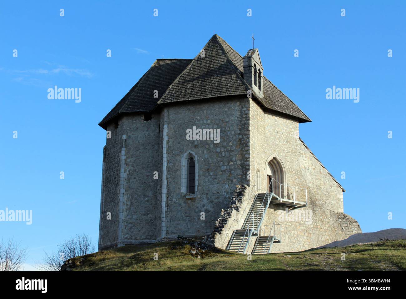 Medieval stone church with steep wooden shingle roof and arched windows ...