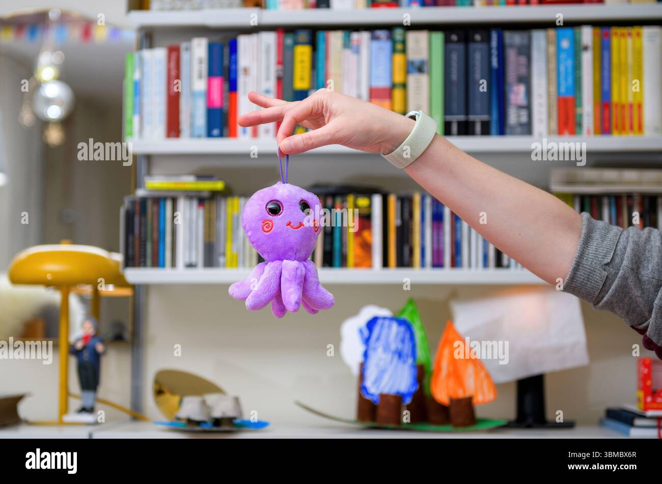 Woman hand wearing a smart band holds a cute purple plush octopus toy ...