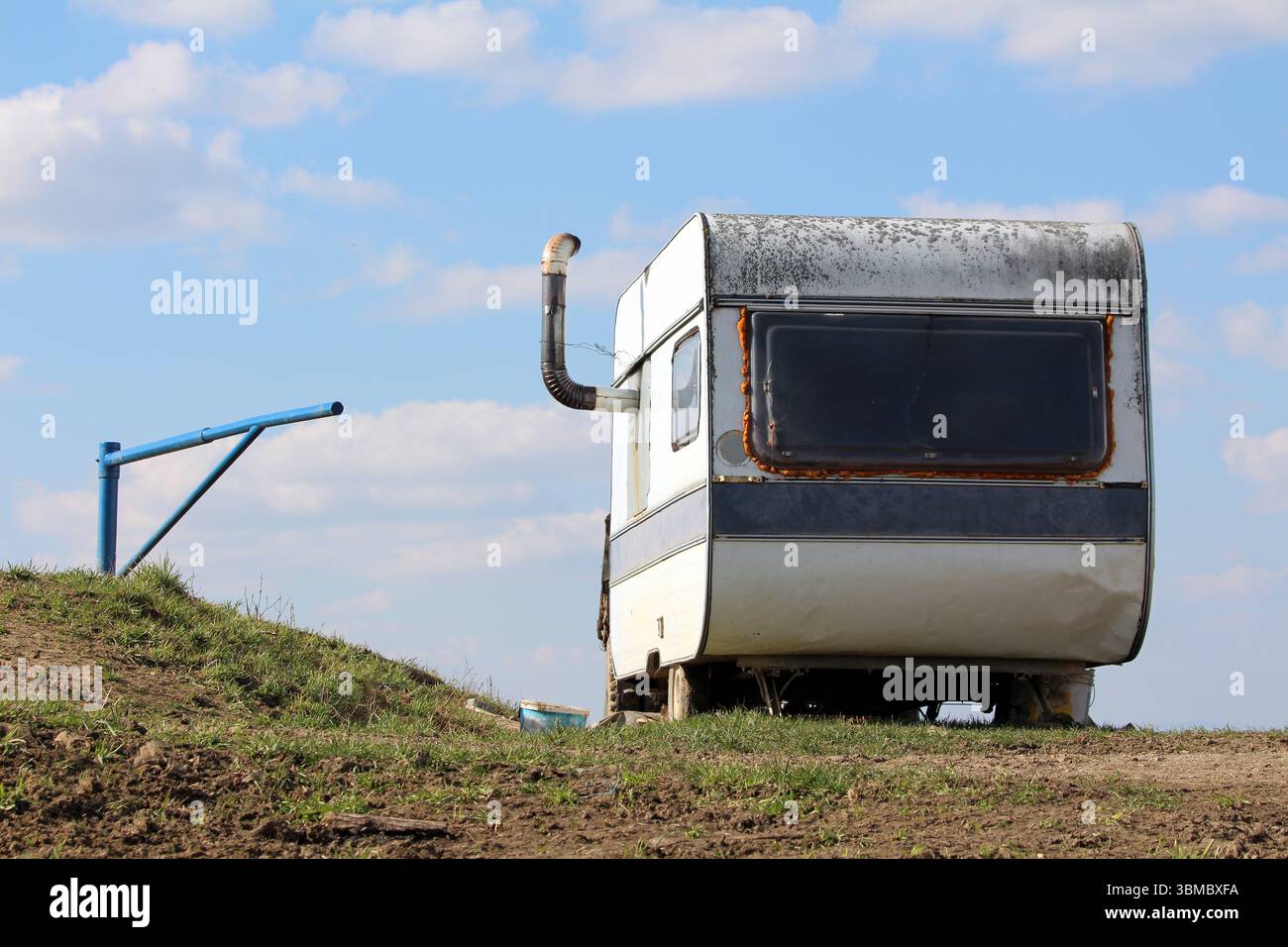 Weathered camper trailer with a rusted window frame and metal chimney ...