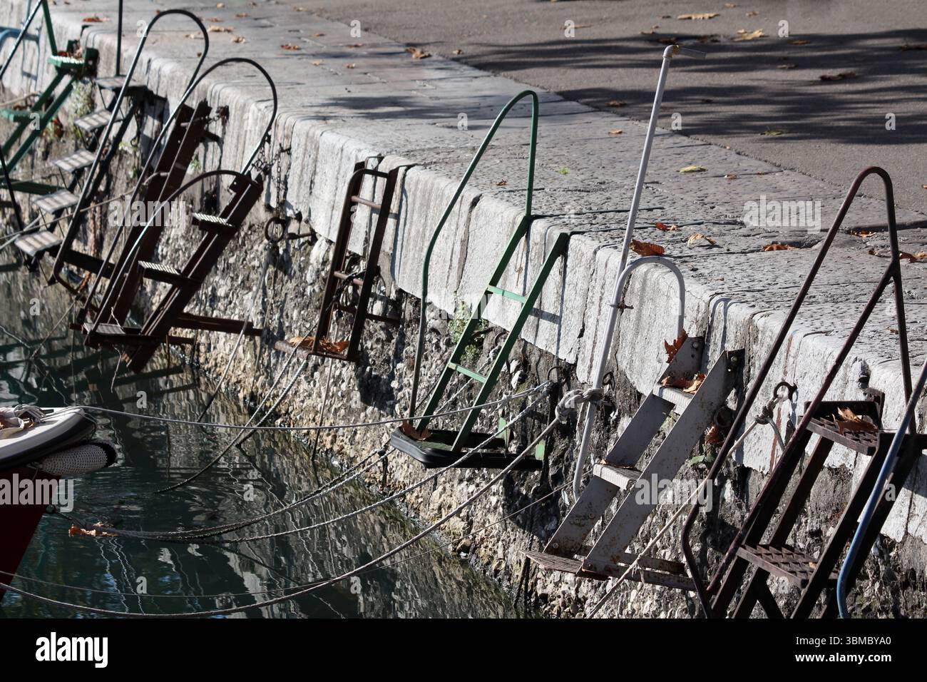 Multiple metal ladders in various colors are fixed to a stone harbor ...