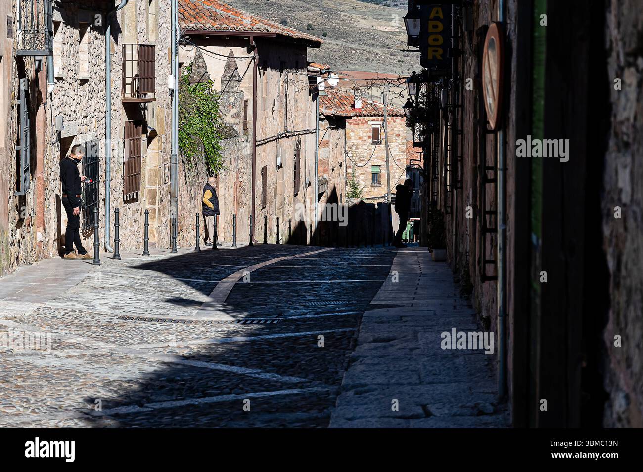 Visitors stroll along a charming cobblestone street in a rustic village ...