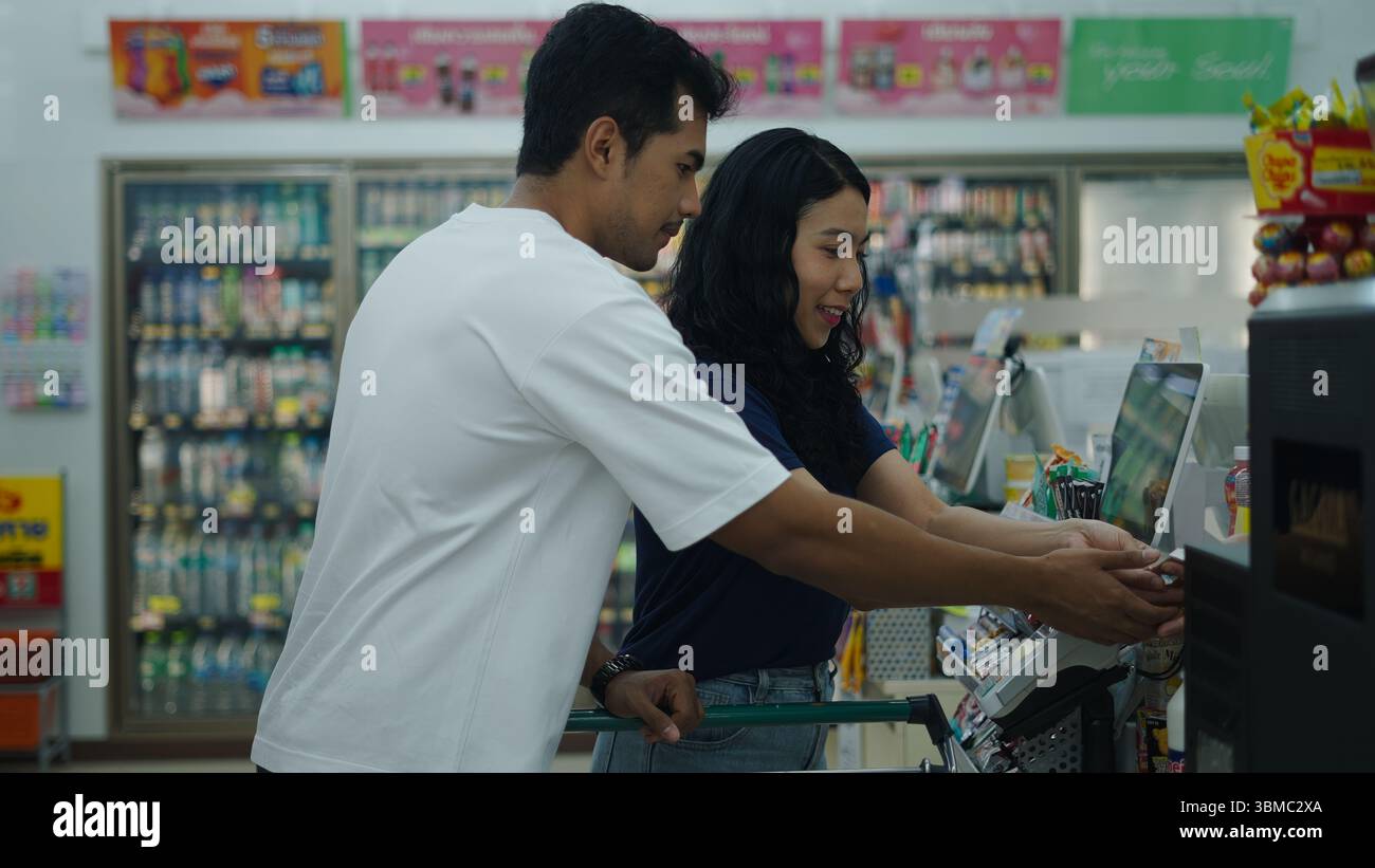 Customers using self checkout counter, paying for groceries in modern ...