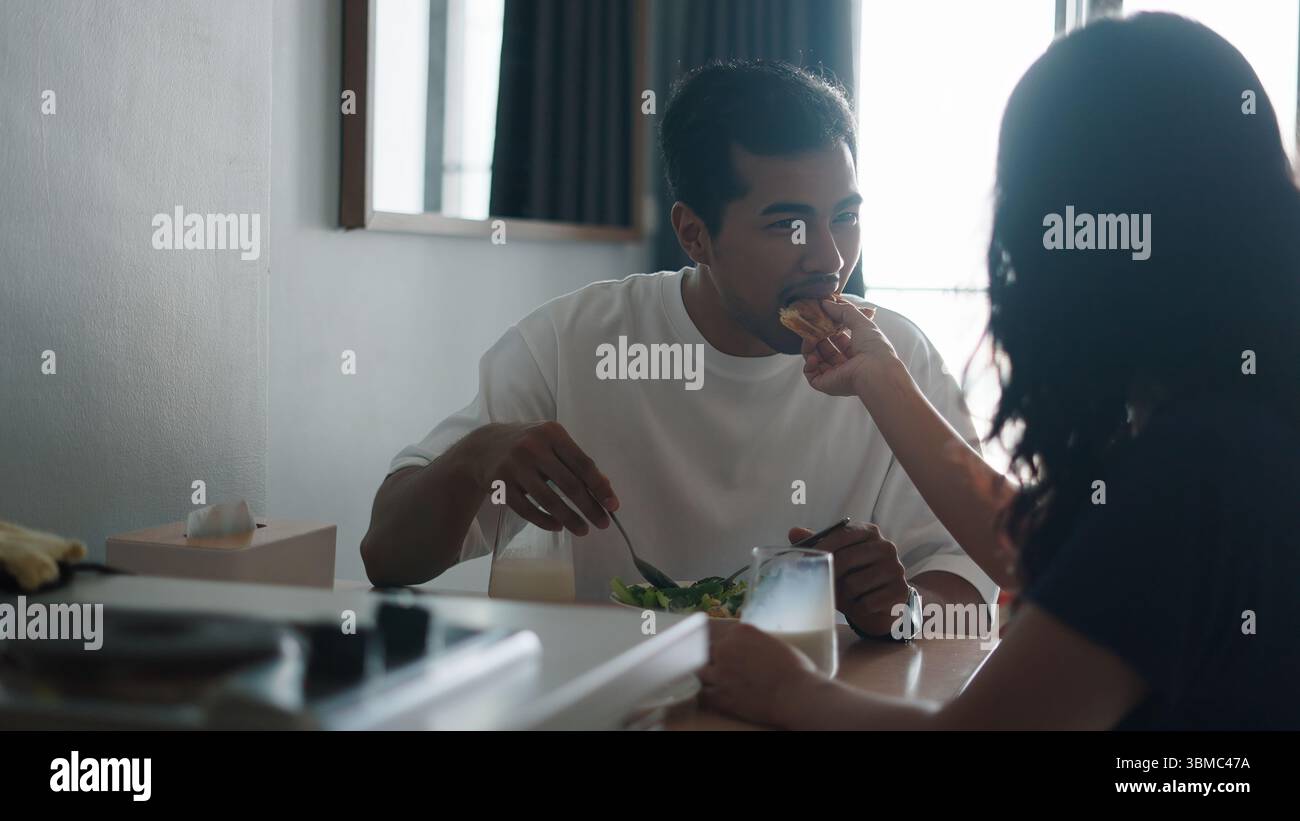 Romantic partners sharing breakfast, smiling while tenderly feeding one ...