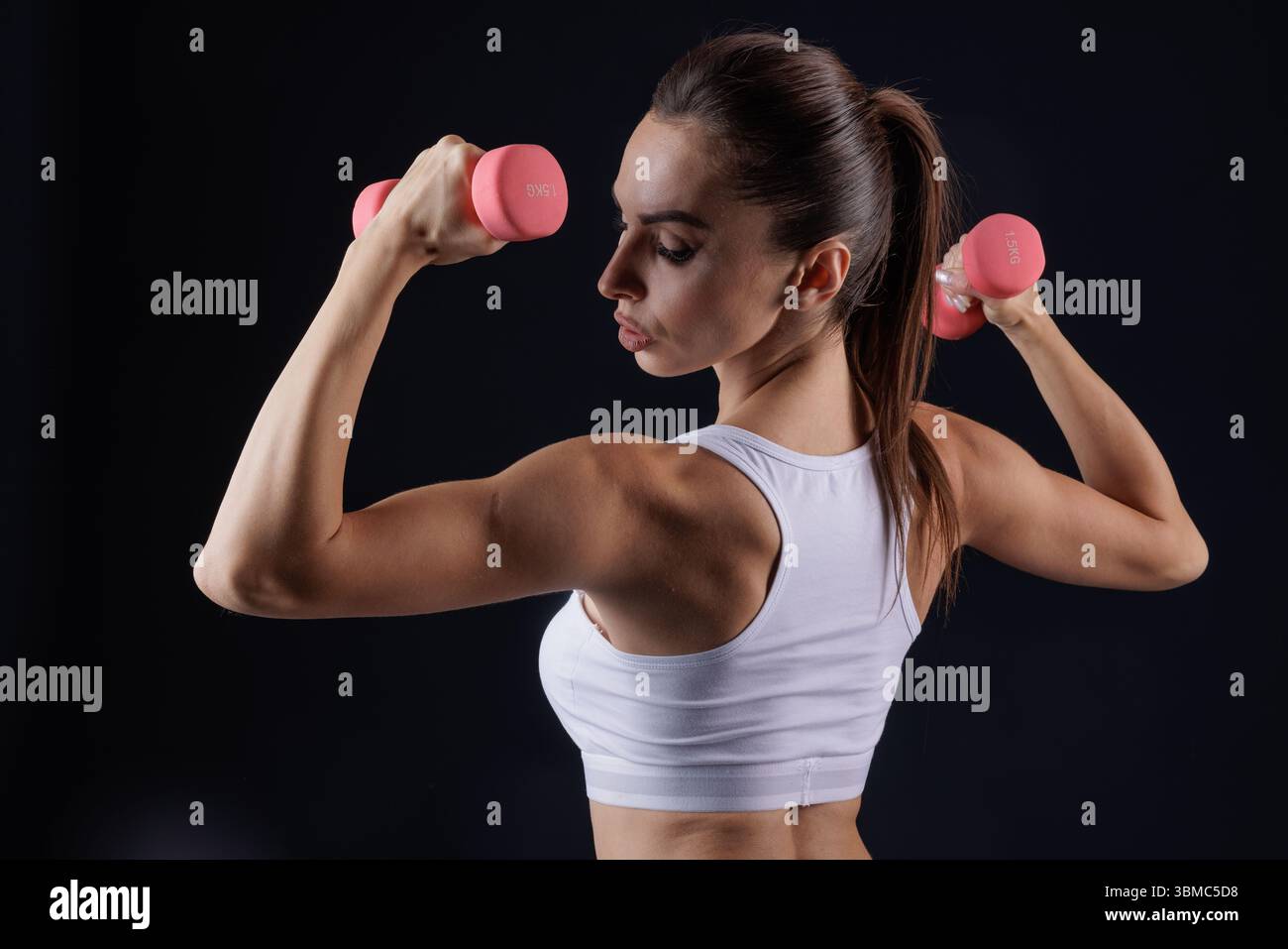 Athletic woman in sportswear flexing back and arm muscles with ...