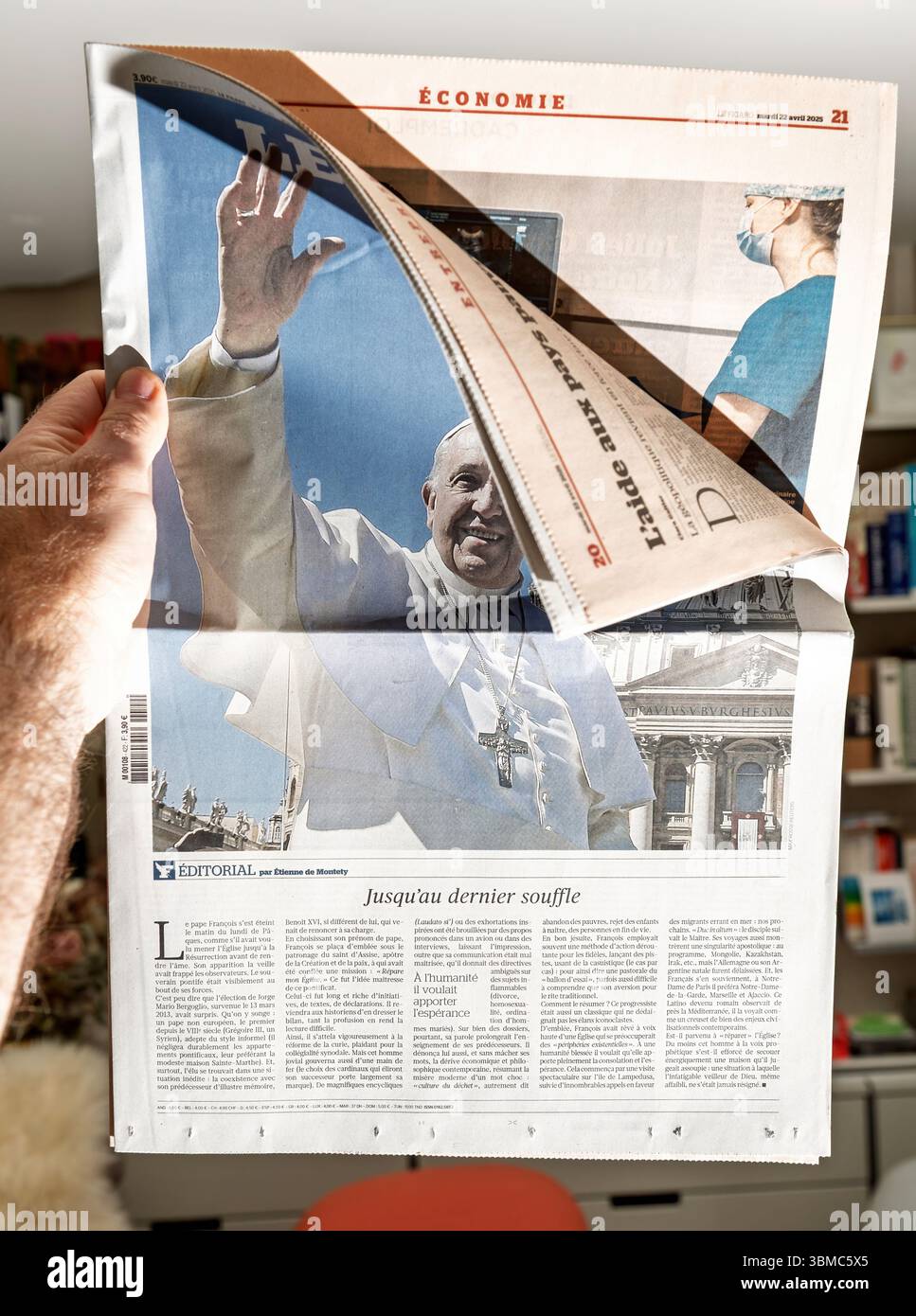 Paris, France - Apr 22, 2025: Person holding a newspaper open to a page ...