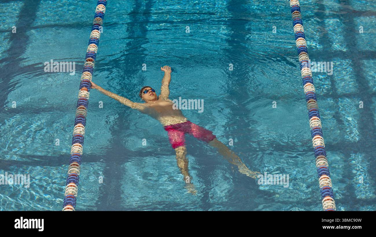 Man floating on back in swimming pool lane with blue water and ...