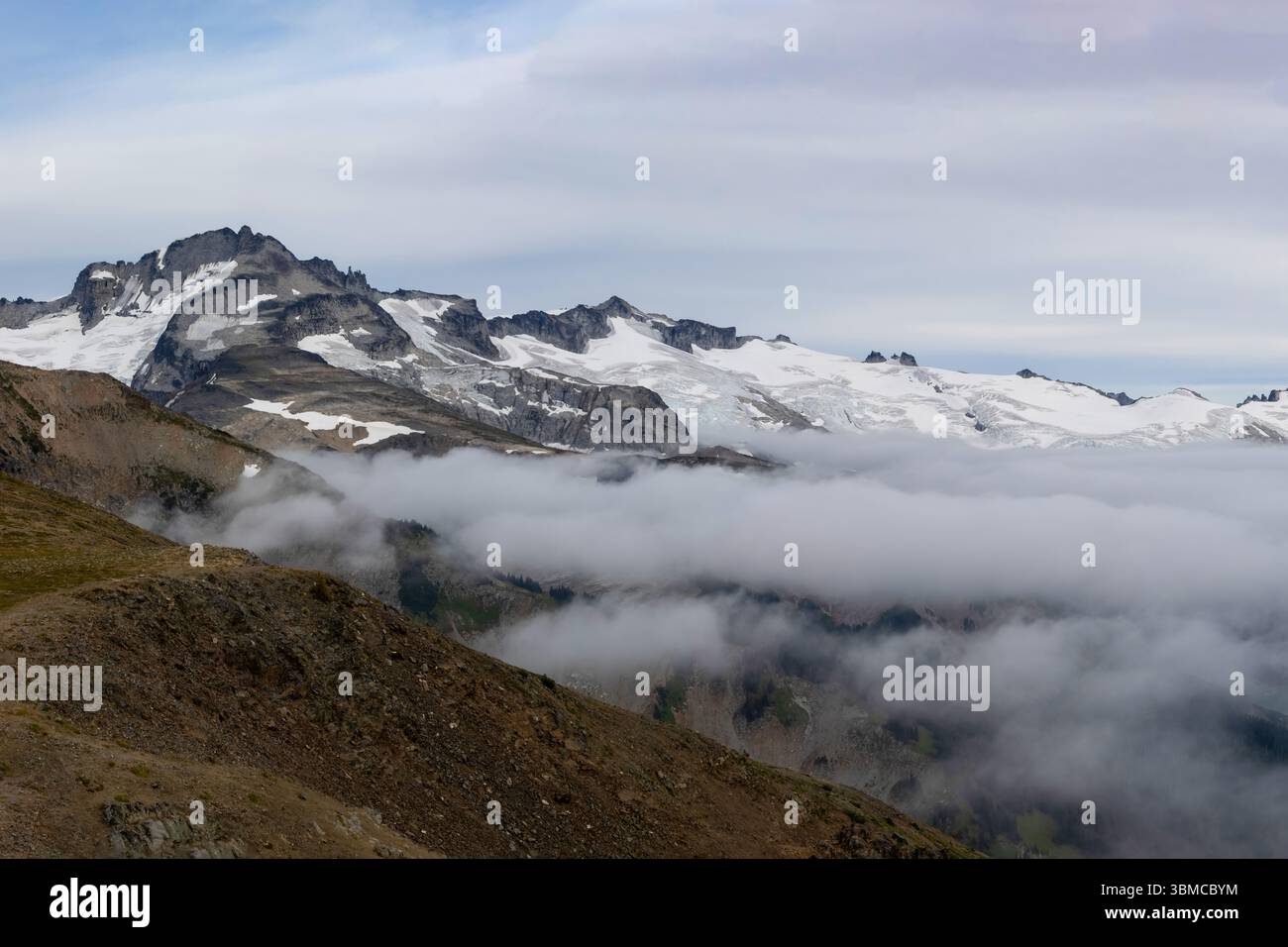 Snowy mountain peaks rise majestically above layers of mist enveloping ...