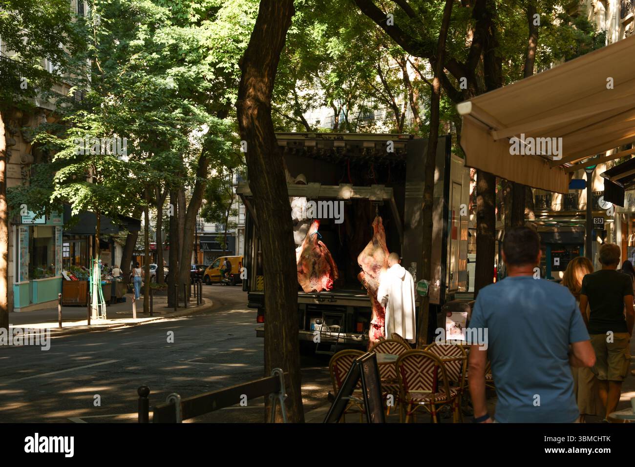 A captivating street scene in Paris features a delivery truck with large beef carcasses hanging ...