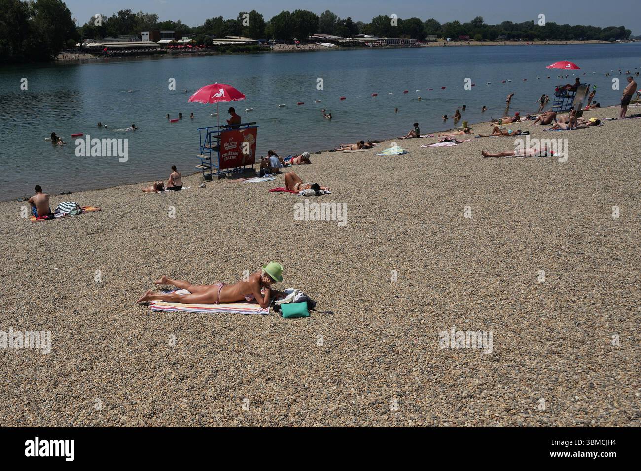 People take sunbath on a warm and sunny day at Ada Ciganlija lake in ...