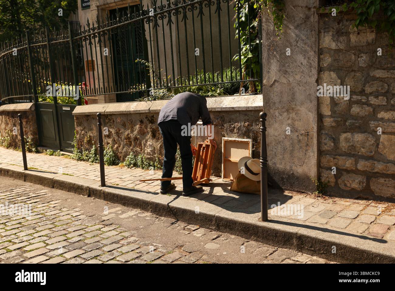 A lone artist carefully folds his wooden easel and gathers his canvas ...