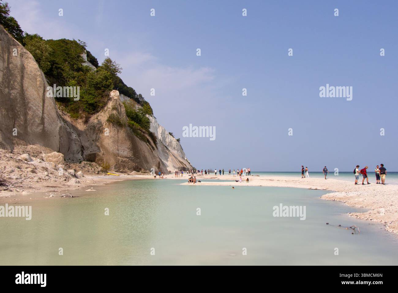 People walking or strolling on white chalky beach with turquoise water ...