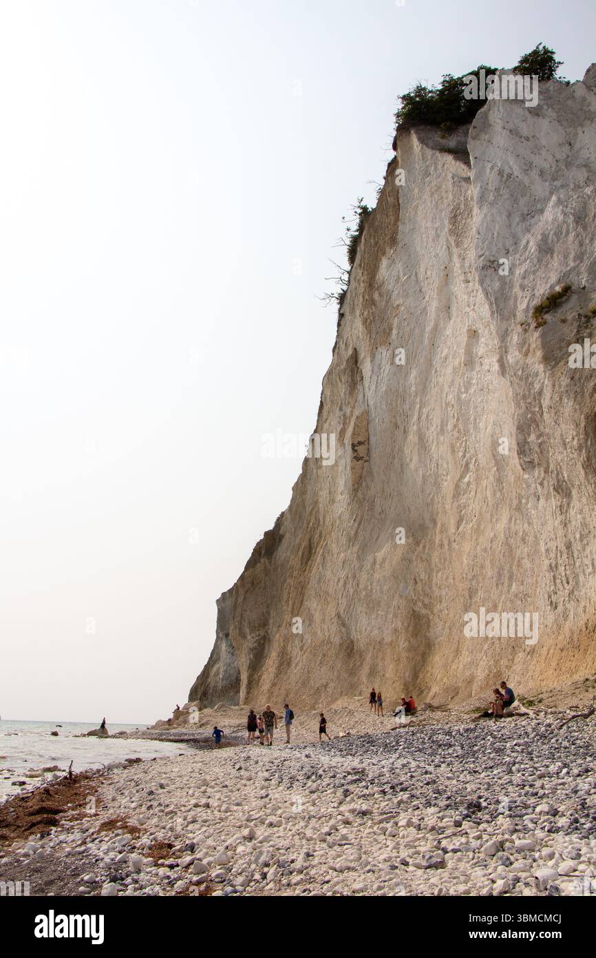 People in the distance exporing the pebble beach with chalk cliffs of ...