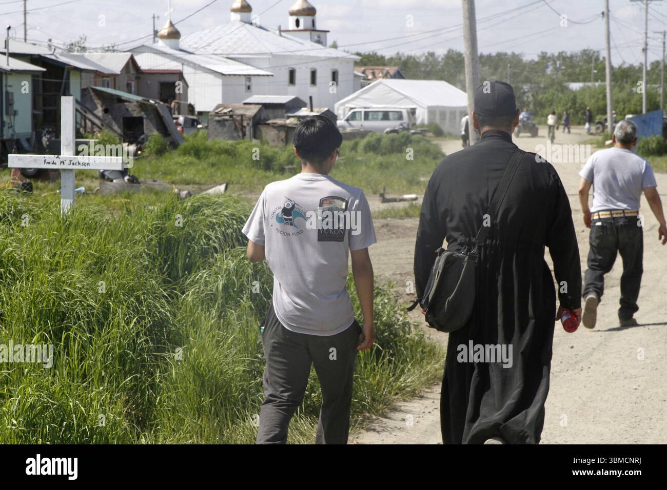 Worshippers, including an Orthodox priest wearing a black cassock, walk ...