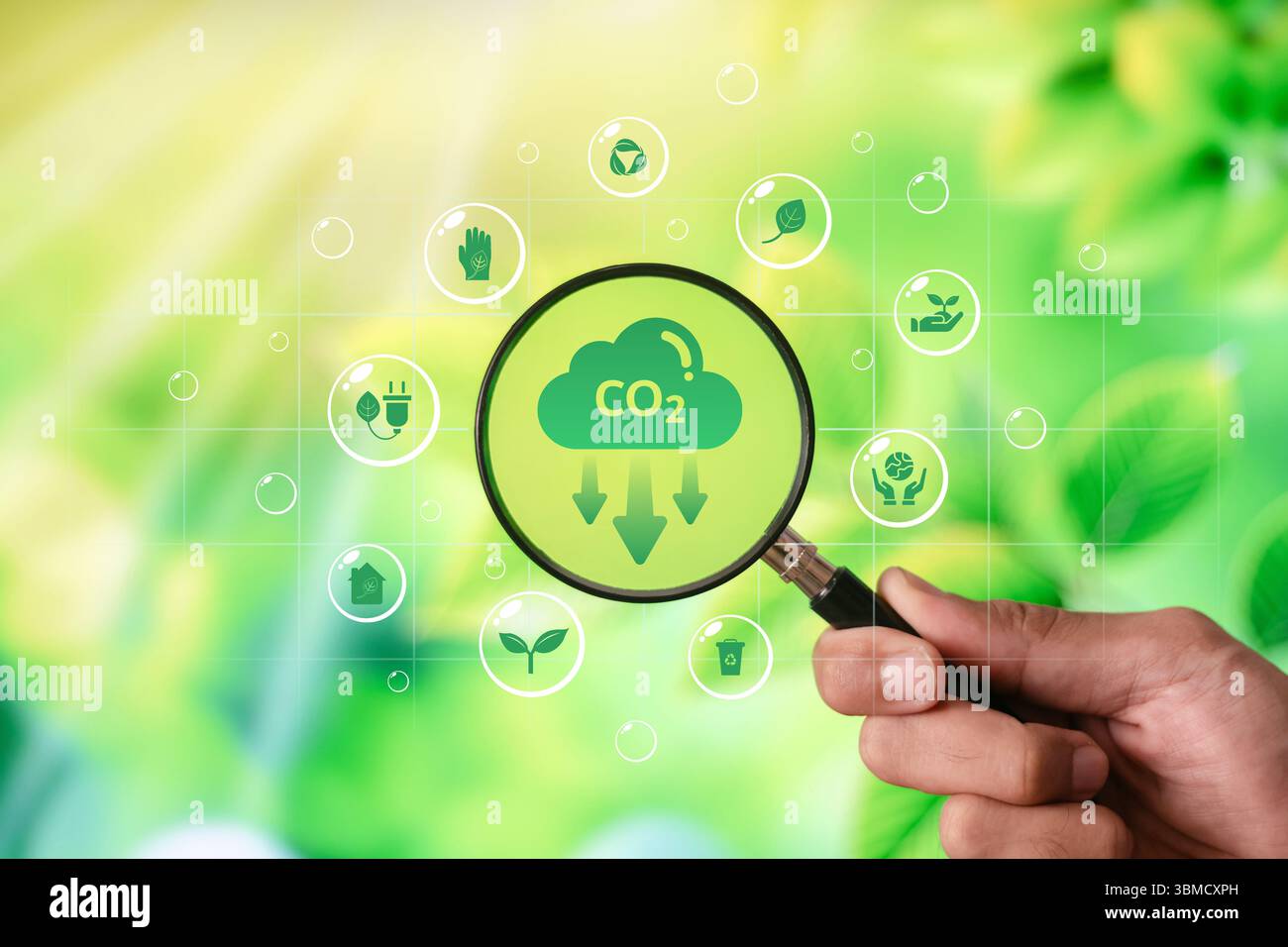 A hand holding a magnifying glass with a green CO2 emissions symbol ...
