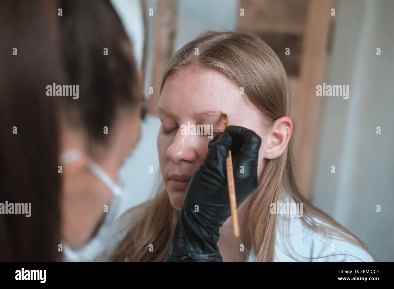 Close-up eyebrows of young blonde woman. A professional colors the ...