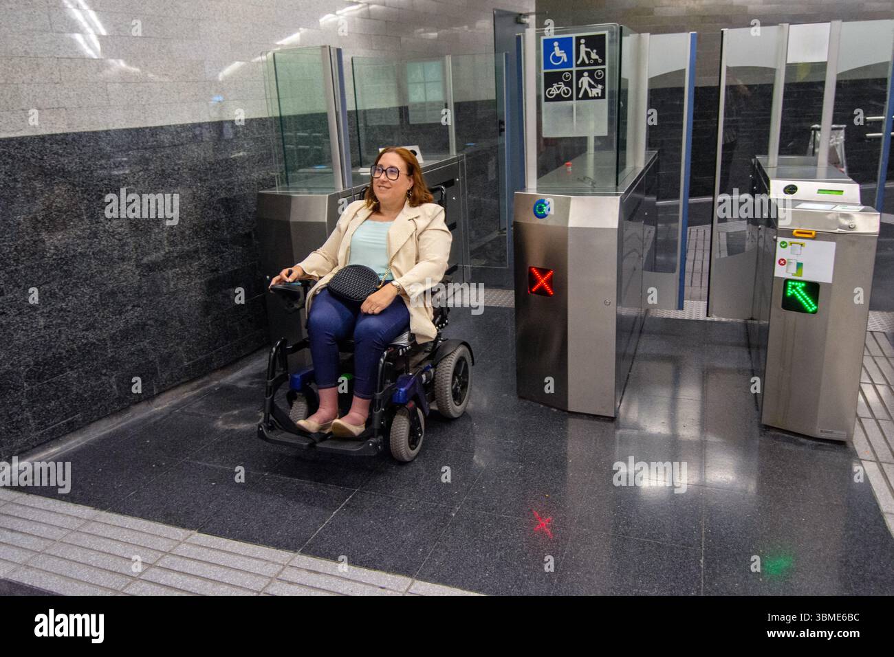 Woman using wheelchair entering subway station through accessible ...