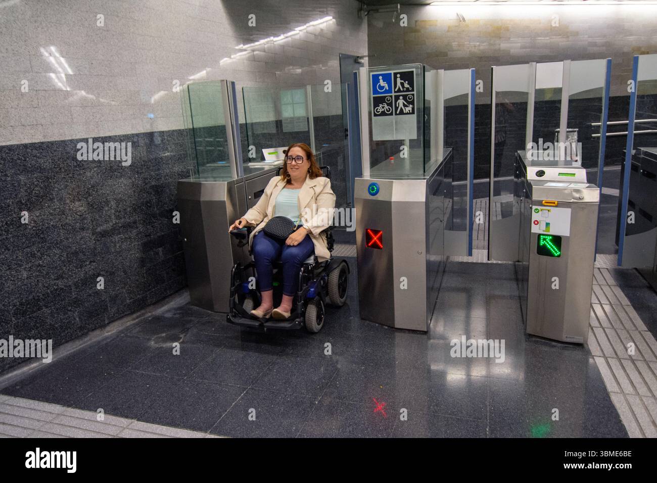 Woman using wheelchair entering subway station through accessible ...