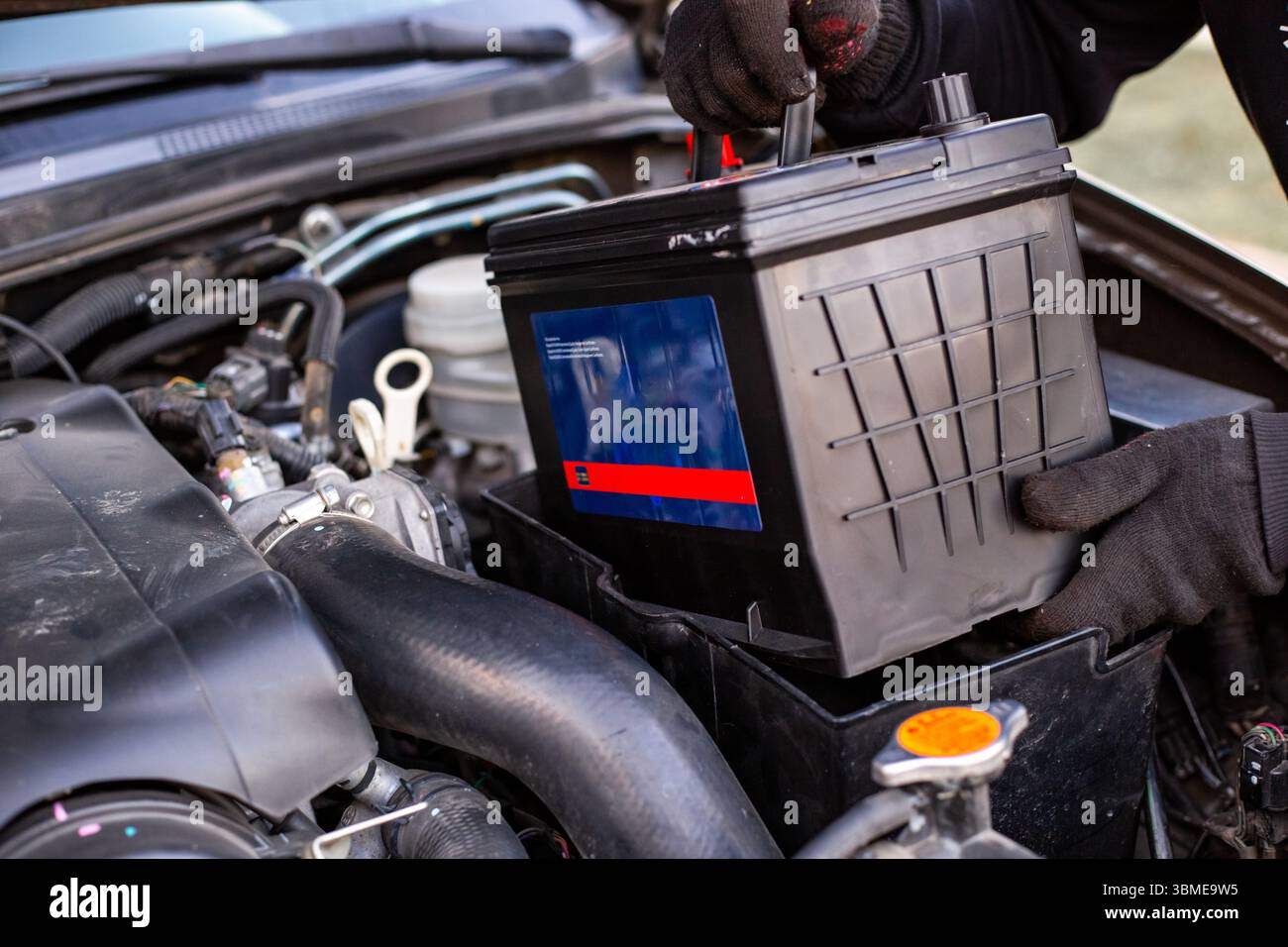 A man wearing black gloves installs a battery into a battery tray in ...
