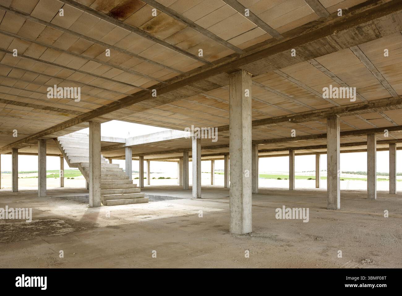 Inside an unfinished building, concrete pillars support the upper ...