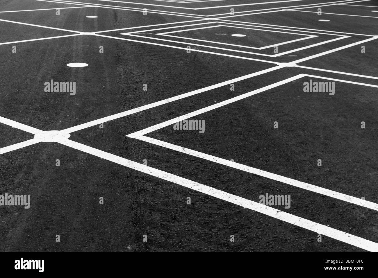 A detailed view of intersecting white lines on an asphalt surface ...