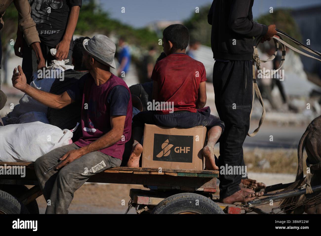 Palestinians carry humanitarian aid packages near the Gaza Humanitarian ...