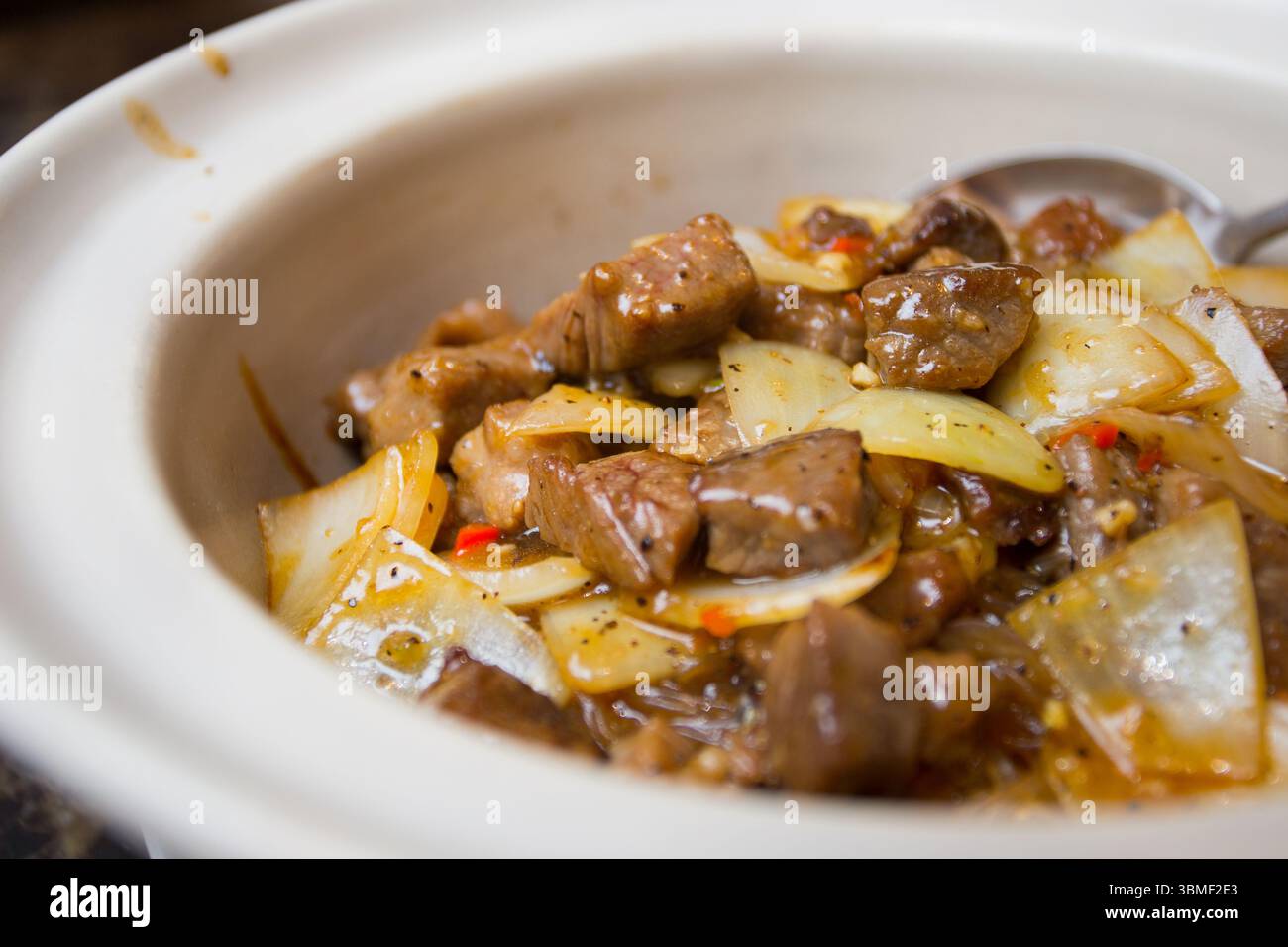 Diced beef with black pepper sauce, served in a traditional clay pot ...